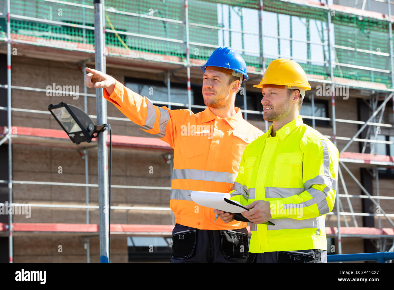A Male Supervisor Looking At Architect Writing On Clipboard Standing At ...