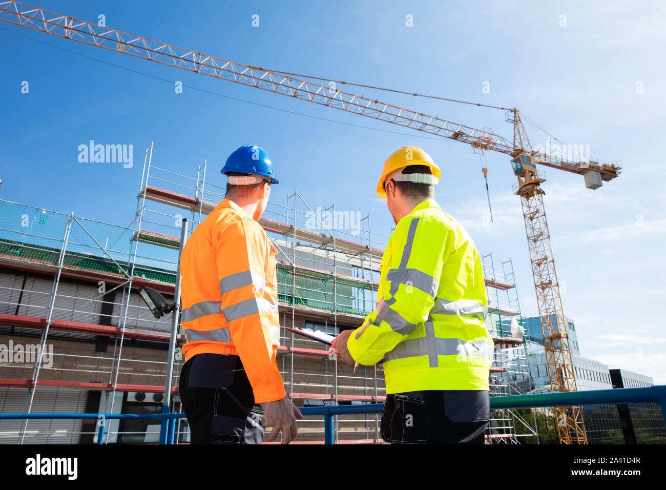 Rear view of two construction workers working at construction site hi ...