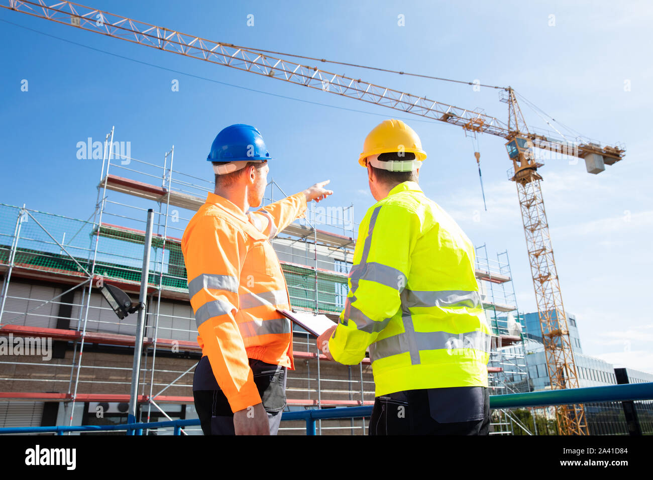 Rear view of two construction workers working at construction site hi ...