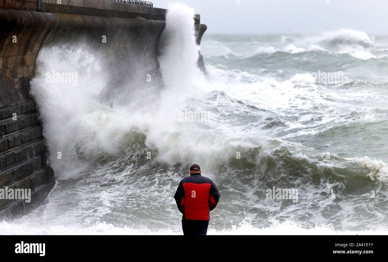 A man watches waves crash on the harbour wall in Dover, Kent, during ...