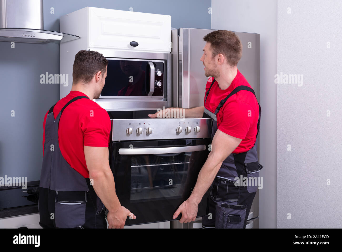 Side View Of Two Young Male Worker Placing Modern Oven Inside The ...