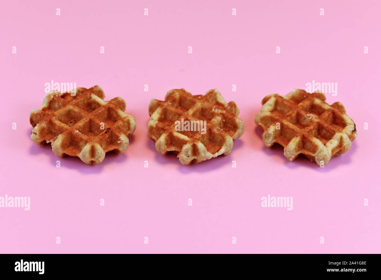 Three round waffles in a row on light pink background Stock Photo - Alamy