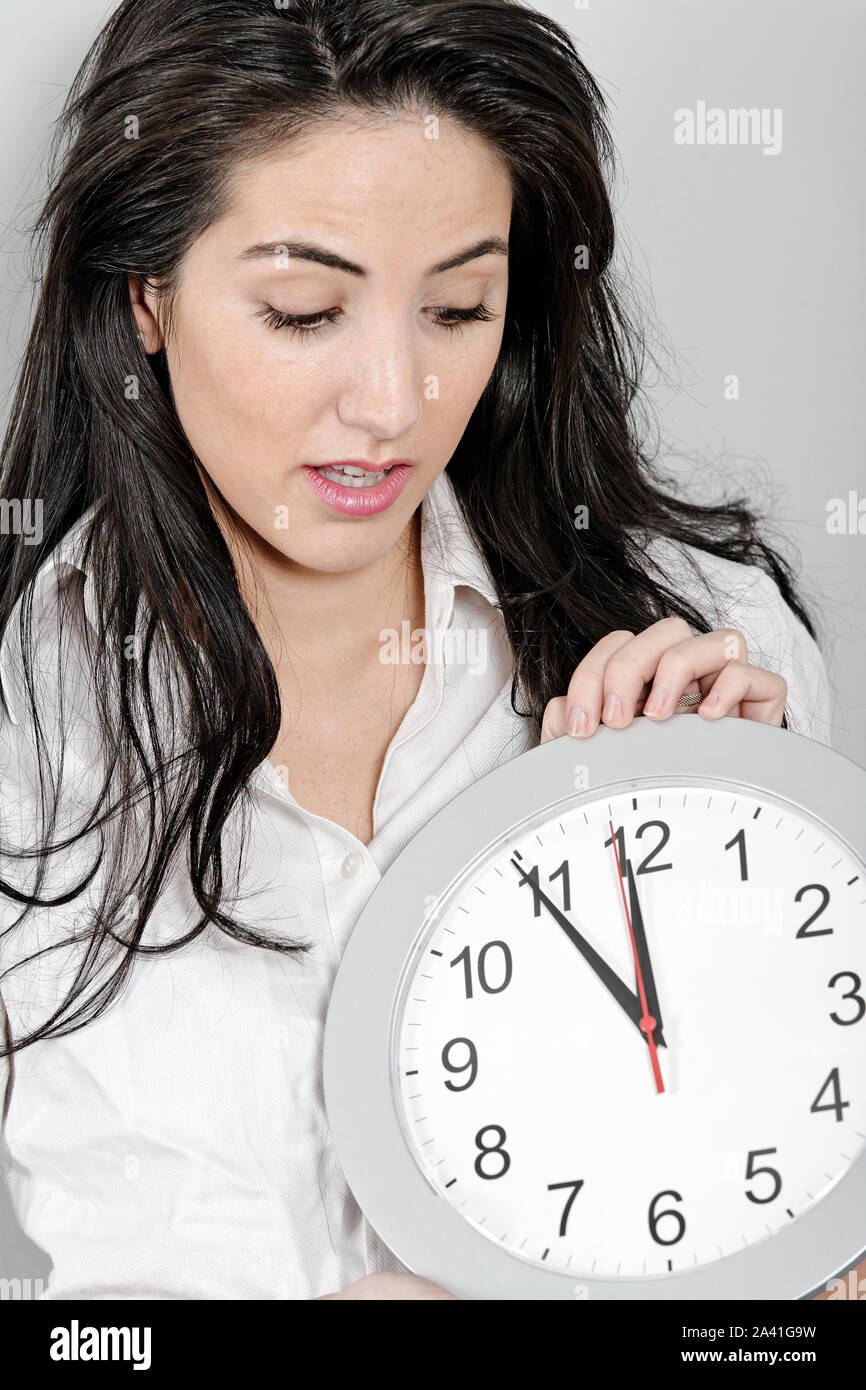 Beautiful young woman holding up a clock face with a worried look Stock ...