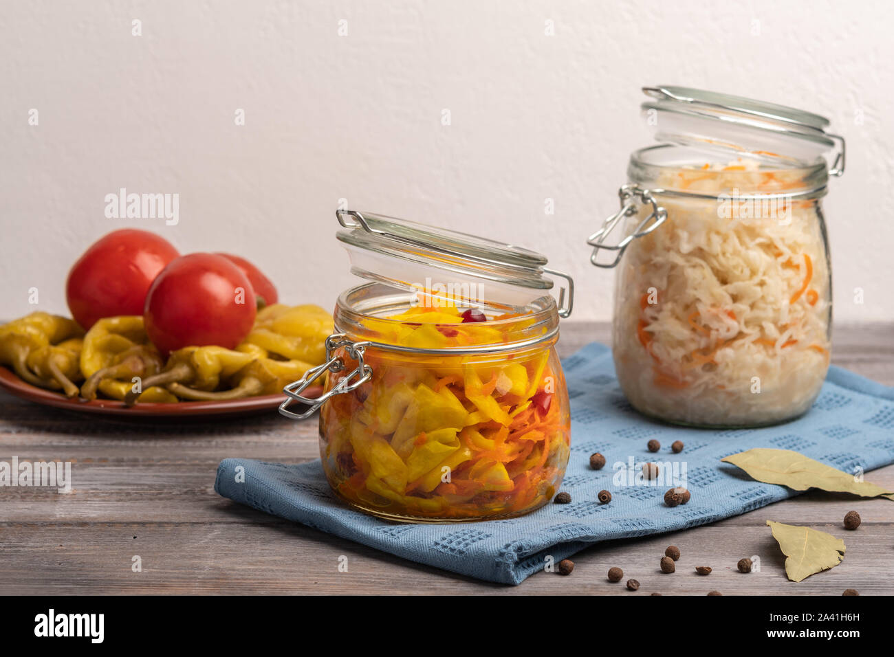 Homemade pickled cabbage in jars and peppers and tomatoes on a ceramic ...