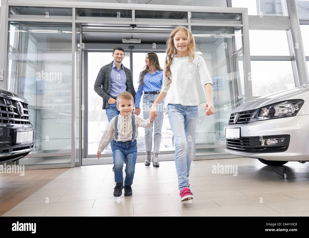 Front view of girl and little boy entering with parents in big auto ...