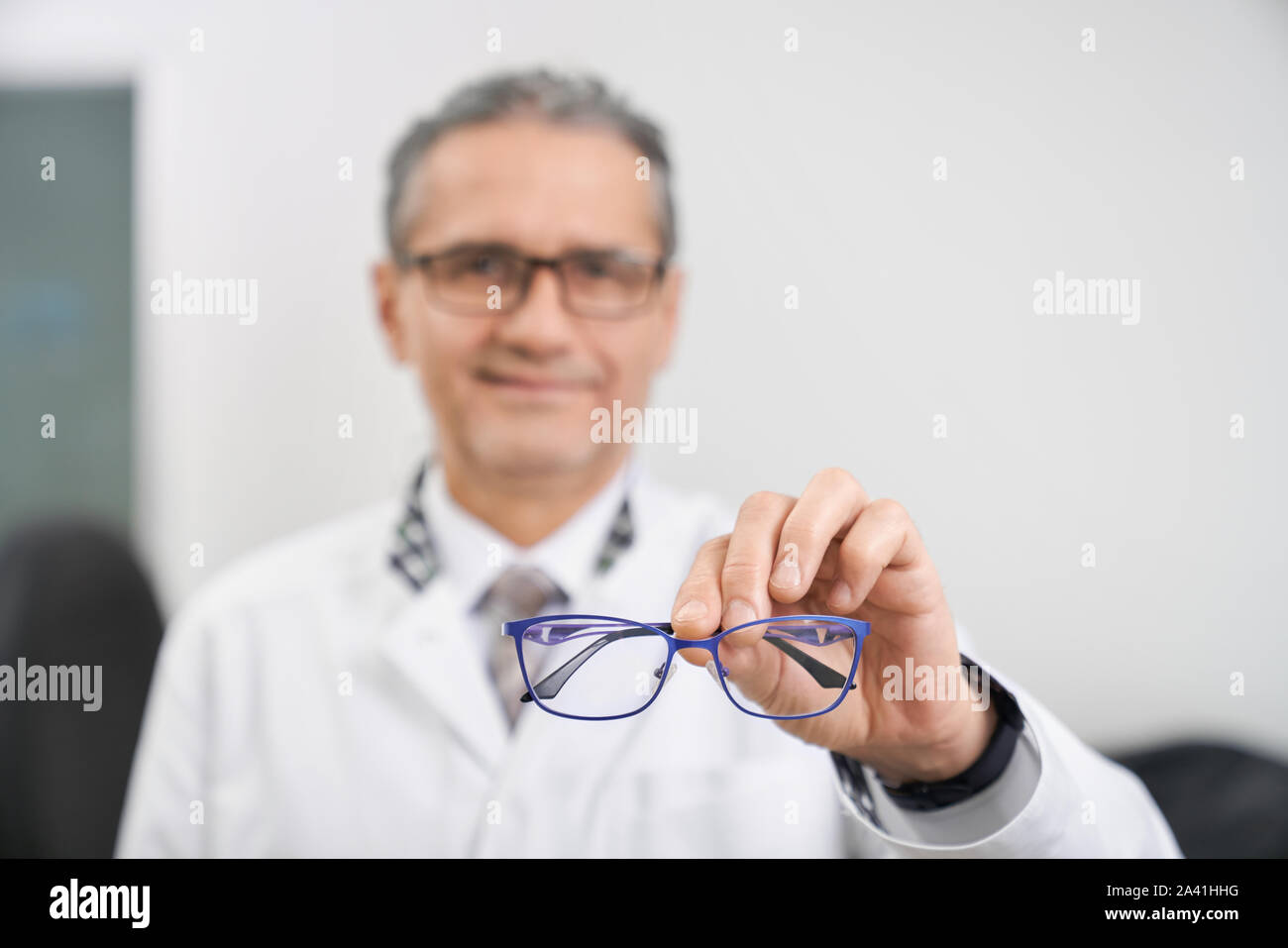 Selective focus of new glasses in hands of male oculist in clinic ...