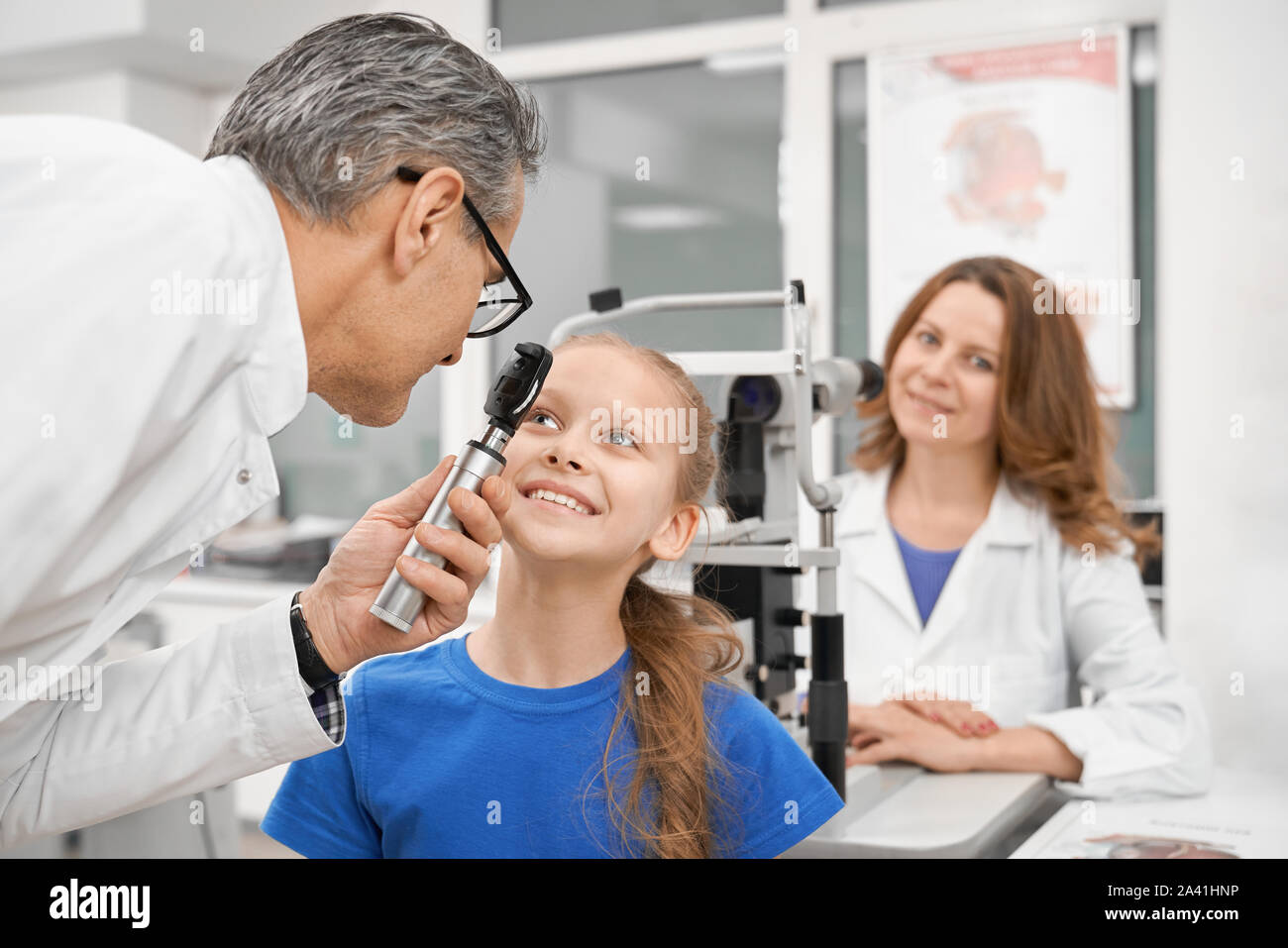 Nice girl checking vision in modern clinic. Clever male oculist wearing ...