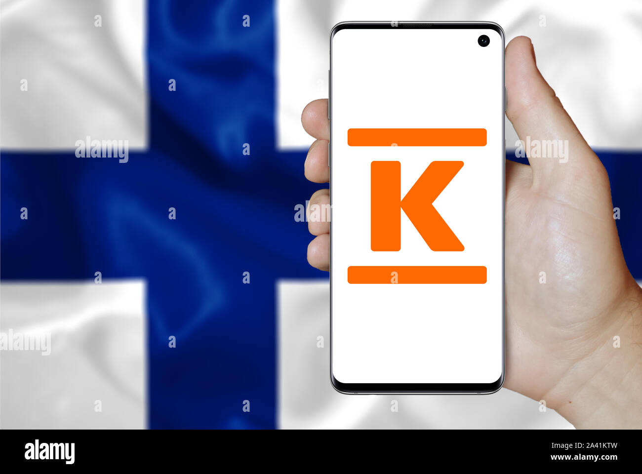 A man holds a phone displaying the logo of company Kesko listed on OMX ...