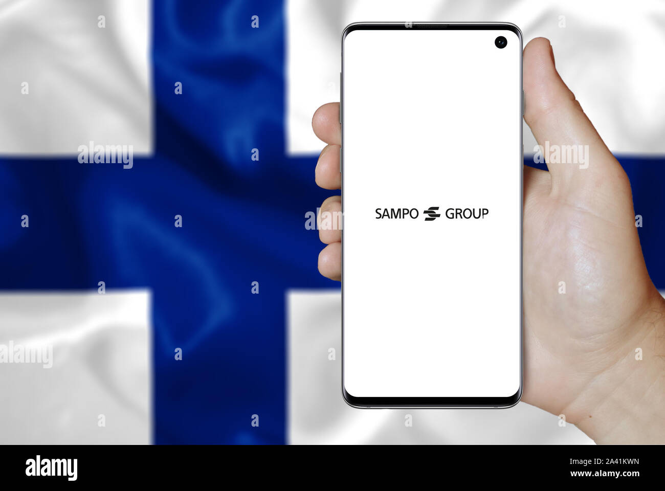 A man holds a phone displaying the logo of company Sampo listed on OMX ...