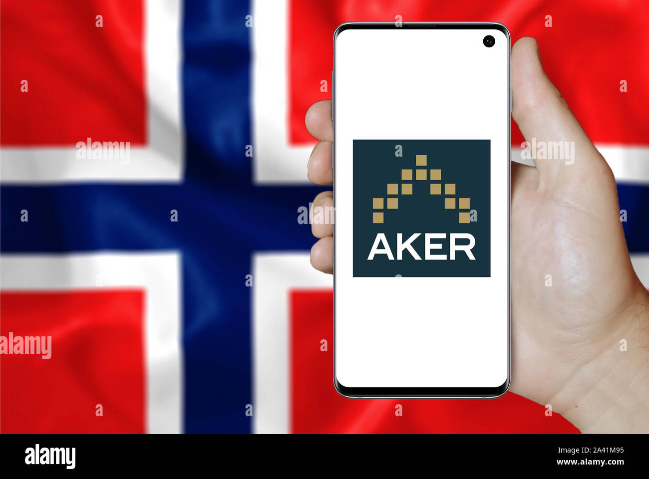 A man holds a phone displaying the logo of company Aker BP listed on ...