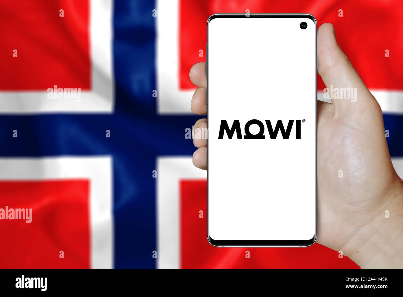 A man holds a phone displaying the logo of company Mowi listed on Oslo ...