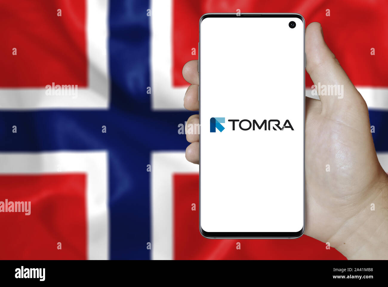 A man holds a phone displaying the logo of company Tomra Systems listed ...