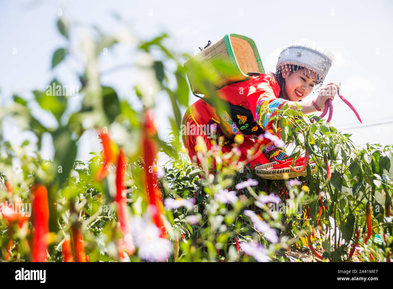 A young Chinese villager dressed in traditional costume of Yi ethnic ...