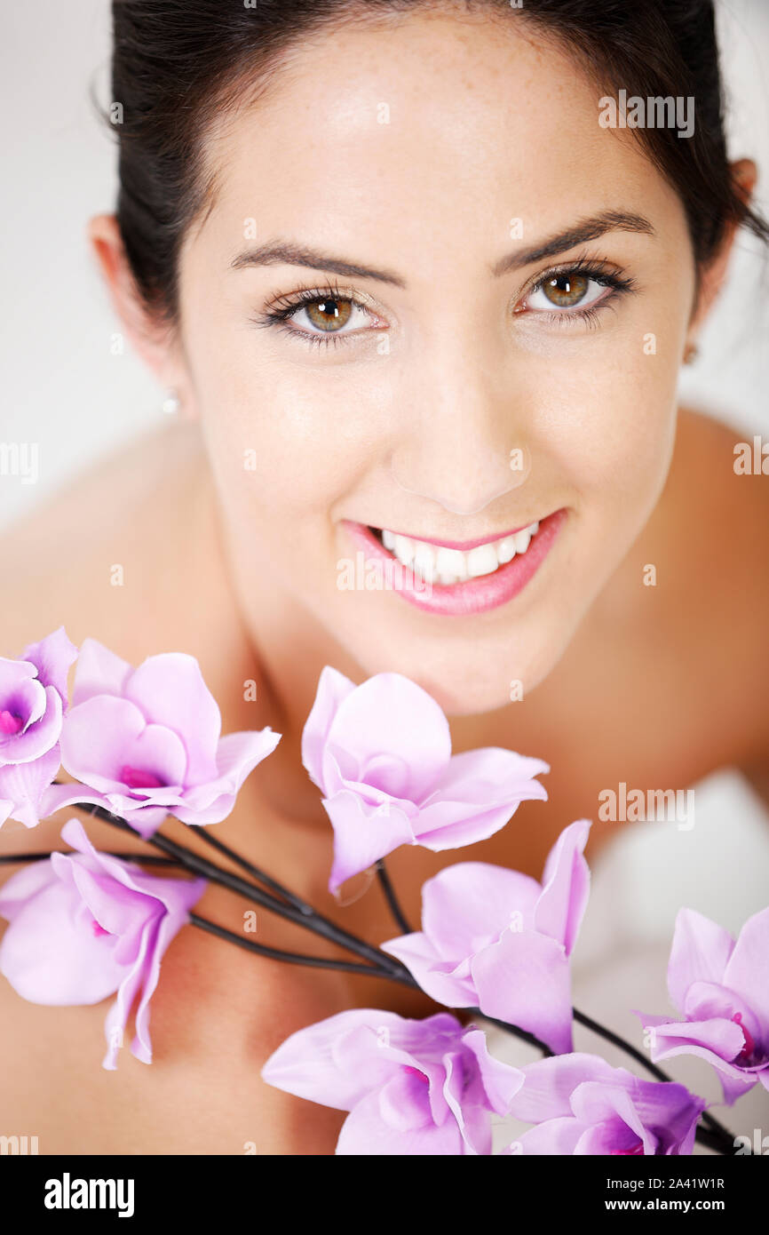 Attractive crop of a woman's face smiling holding purple Orchid's Stock ...