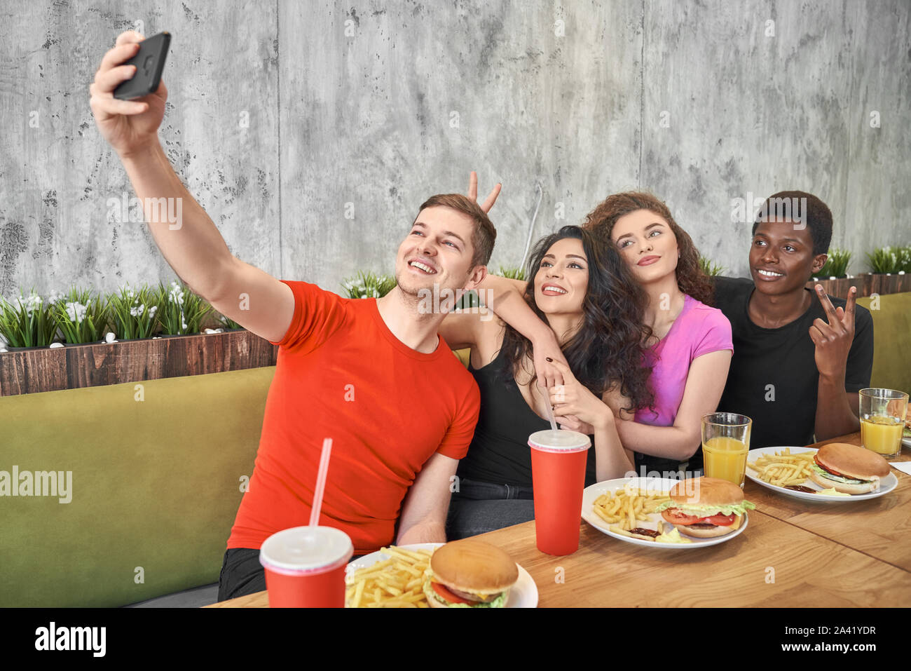 Friendly company doing selfie together in cafe while having lunch ...