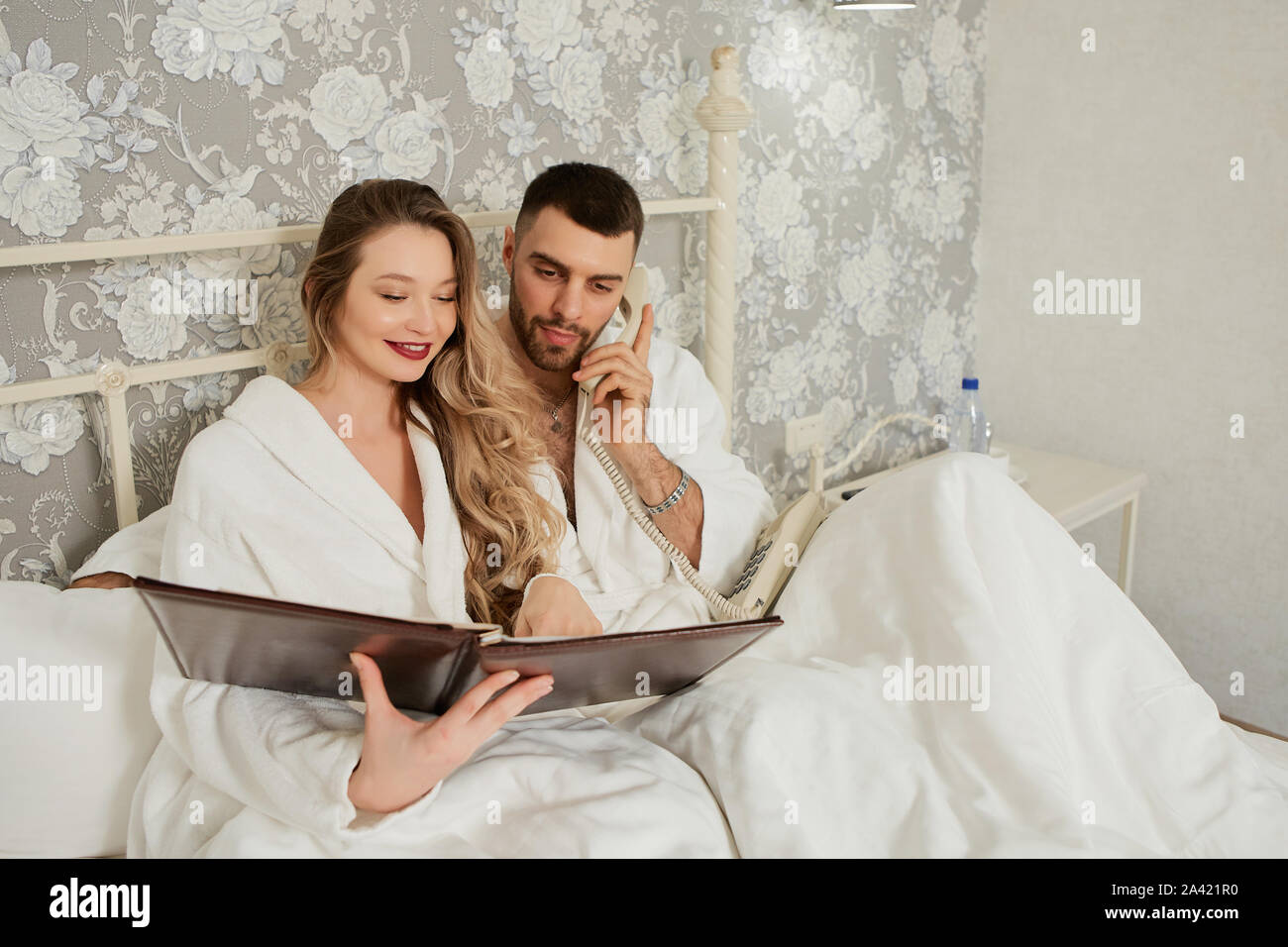Couple with menu calling room service for food from hotel room Stock ...