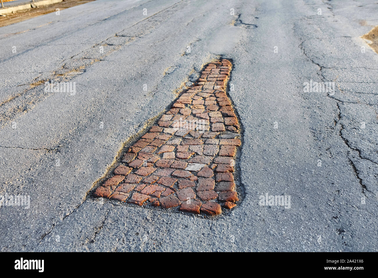 A large pit on the road, laid with old bricks. The repair of the road ...