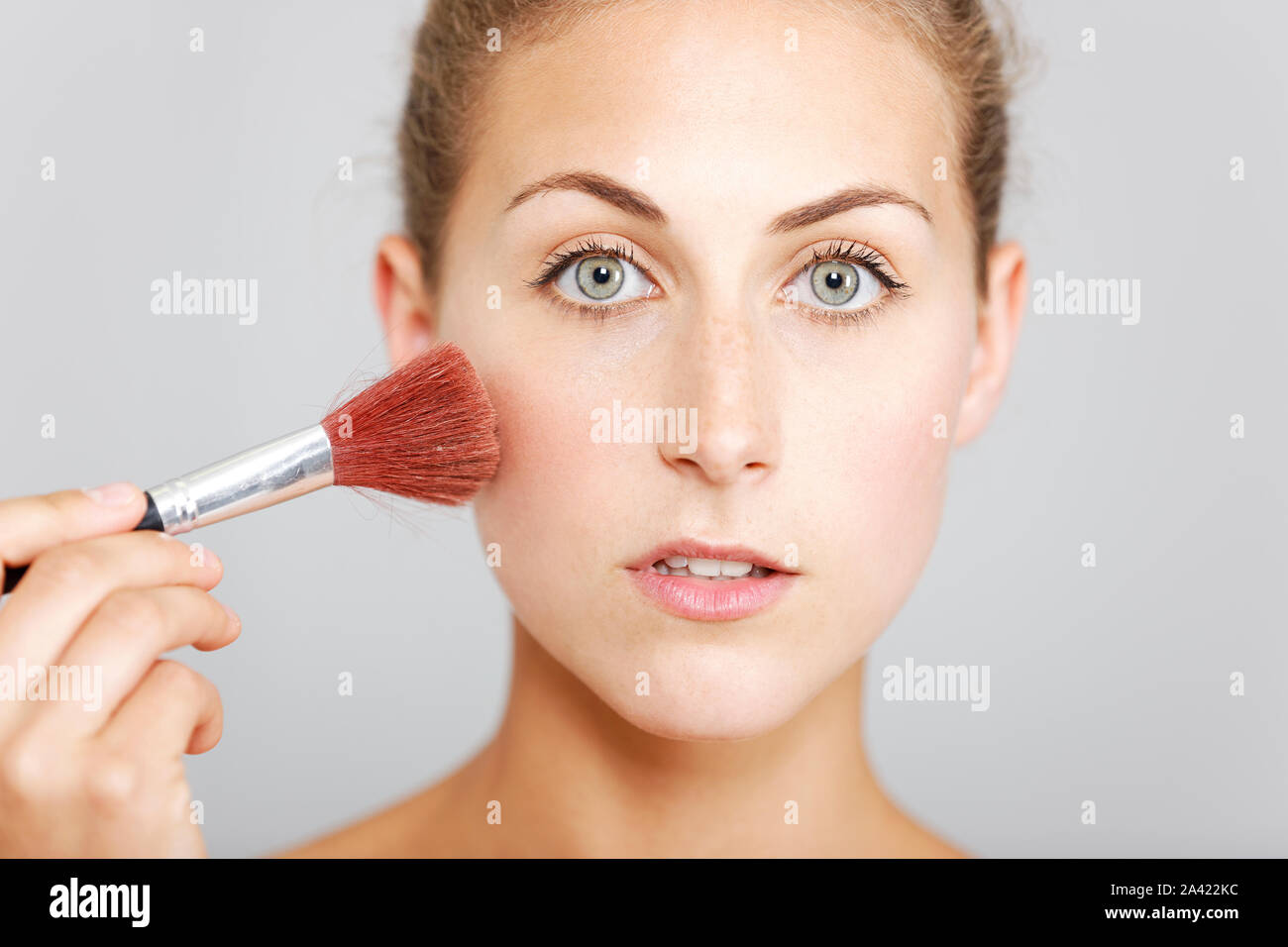 Attractive young woman applying make up Stock Photo - Alamy