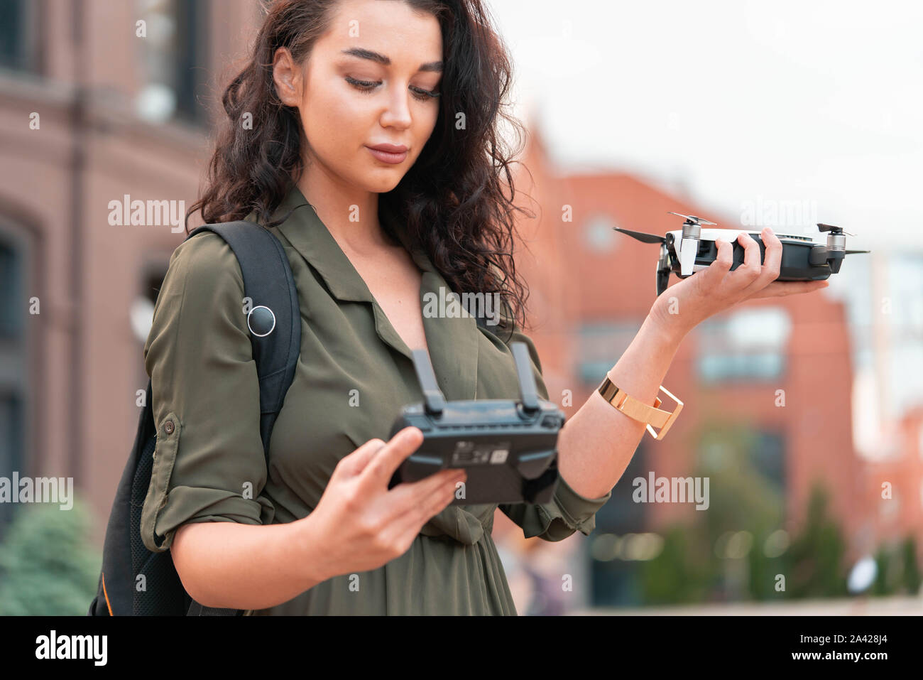 Young beautiful woman launching drone quadcopter at urban background ...