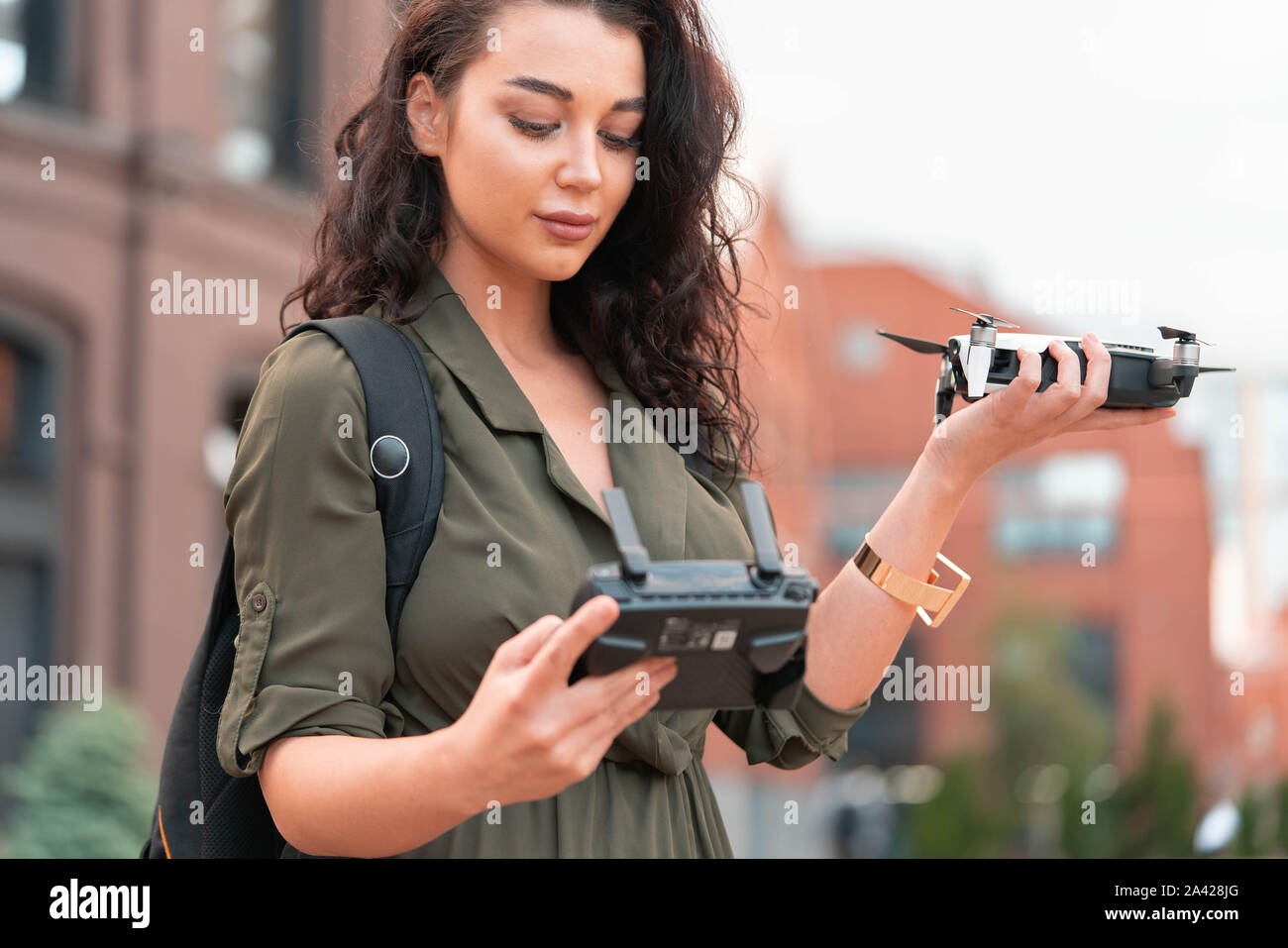 Young beautiful woman launching drone quadcopter at urban background ...