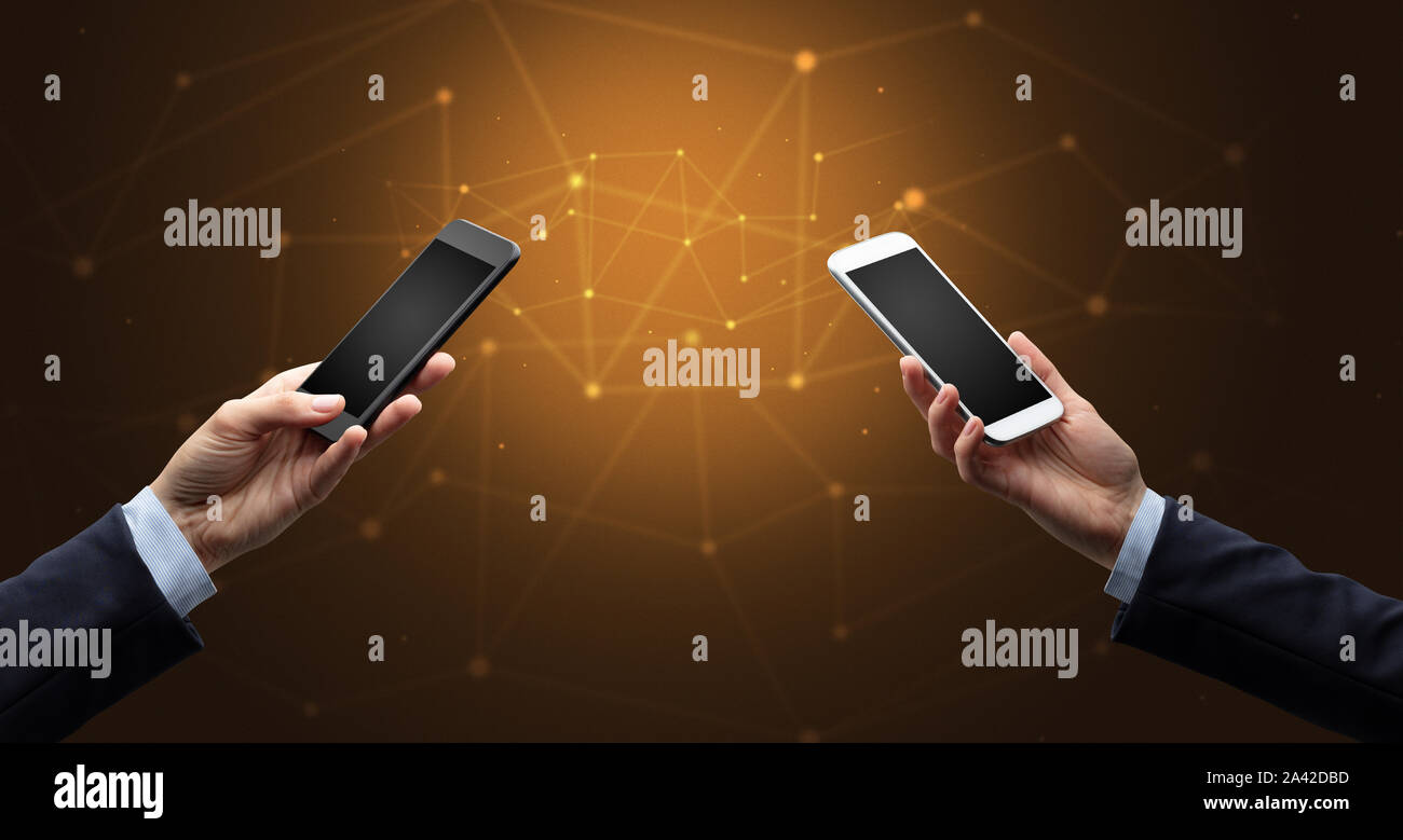 Close up of two hands holding smartphones to each other, wireless ...