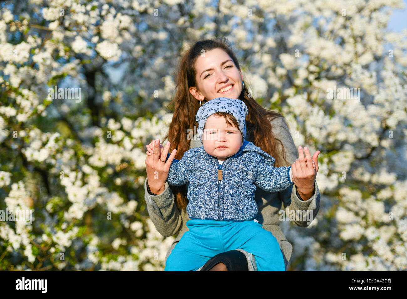 Toddler with mom on the background of flowering trees. little baby on ...
