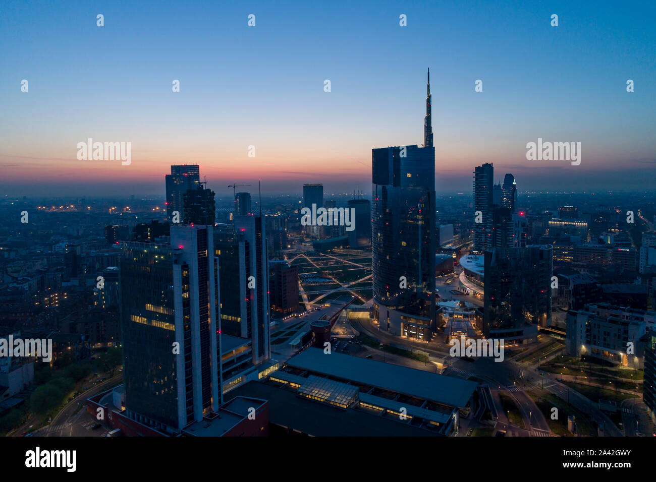 Aerial night view of Milan before sunrise. Flying over building and ...