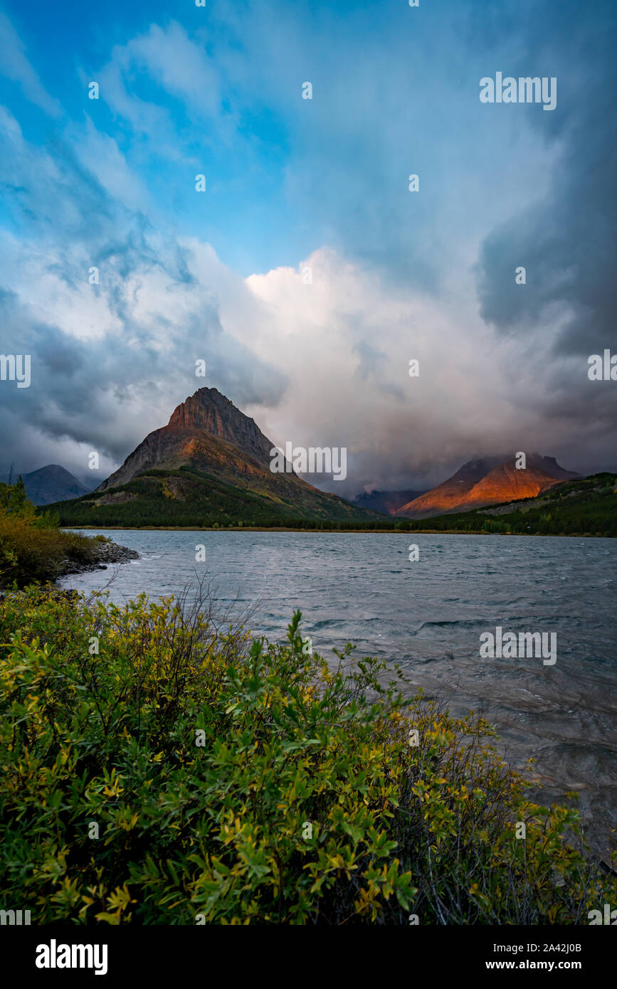 The sunrise lighting up the mountains in the background of Swiftcurrent ...