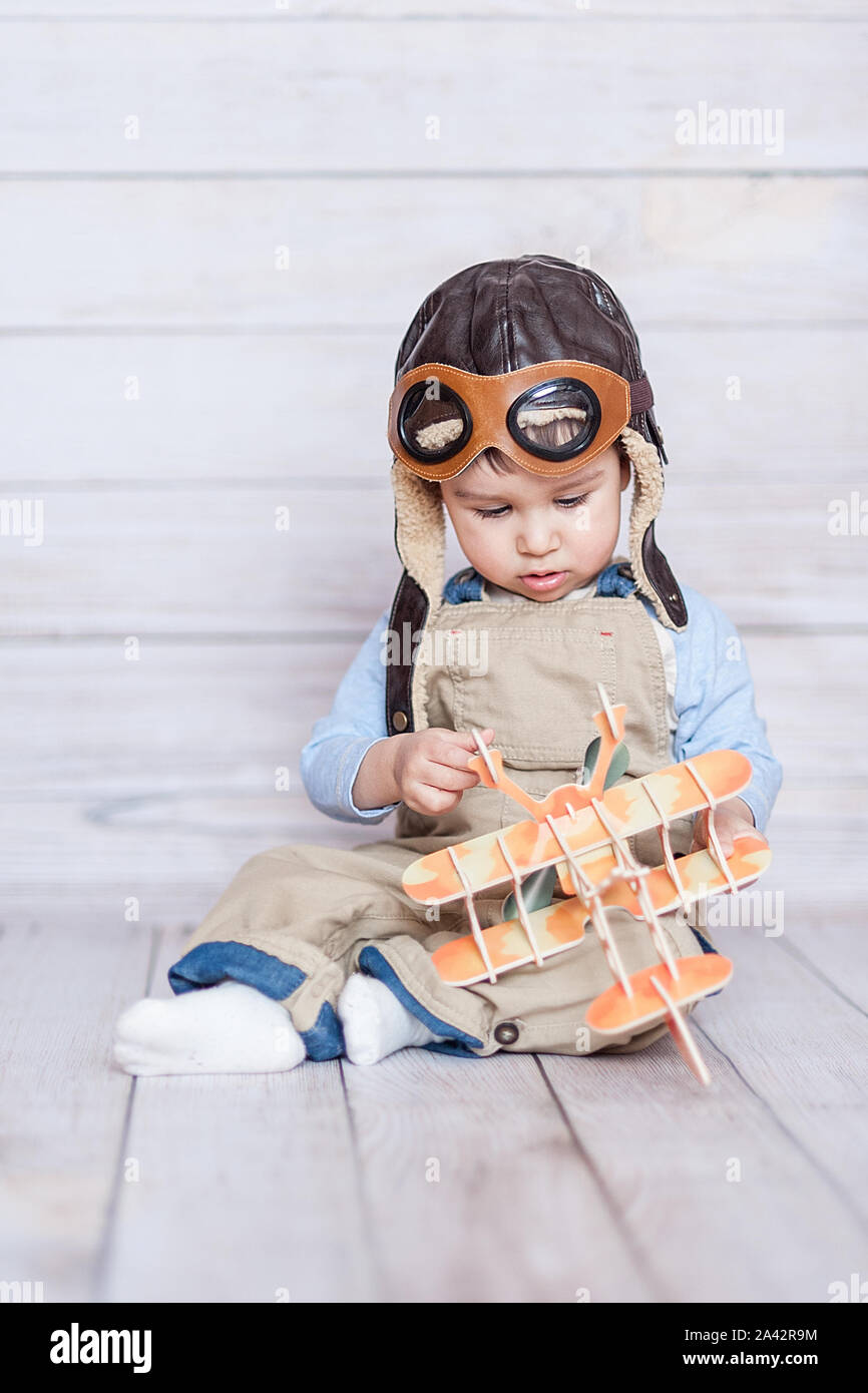 cute smiling baby in the cap of the pilot and wooden model of airplain ...
