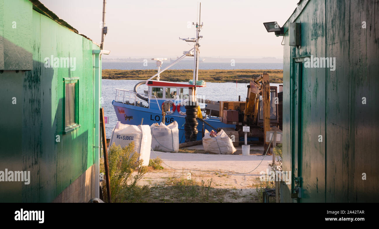 A cockle boat is seen between the green walls of cockle sheds at Leigh ...