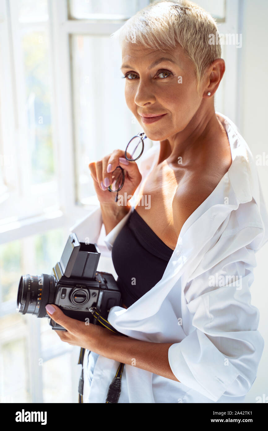 Good idea. Cheerful photographer keeping smile on her face and standing ...