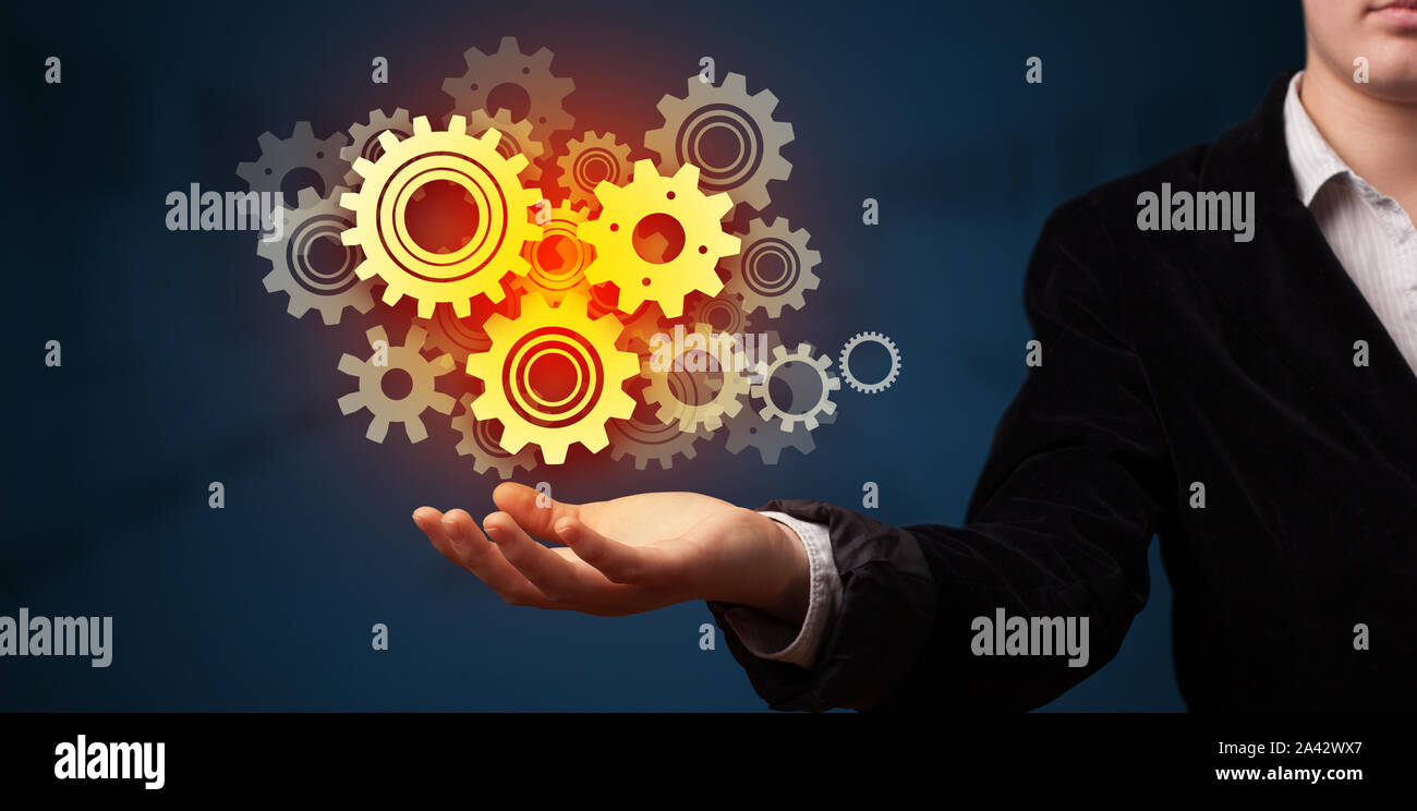 Hand holding gears in his hand Stock Photo - Alamy