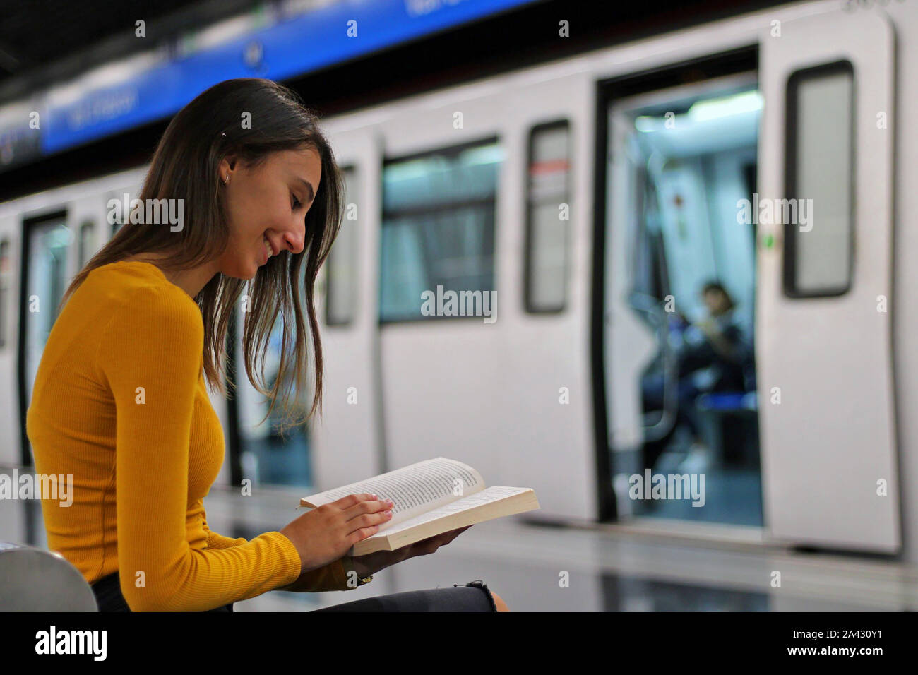 Beautiful young girl dressed in yellow reading a book while waiting for ...