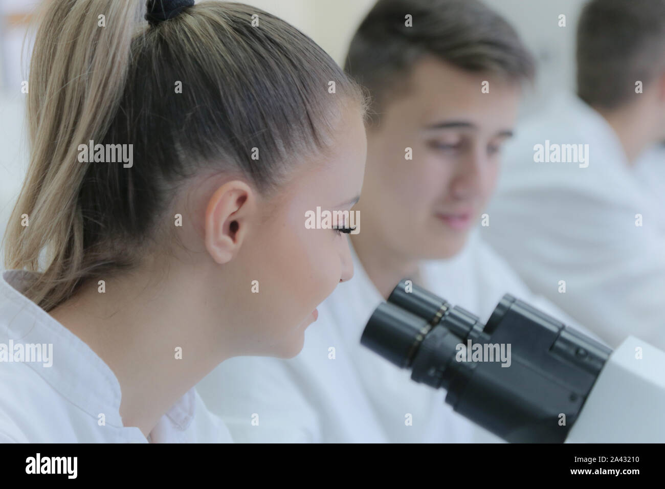Two young male and female students scientists doing experiments in ...
