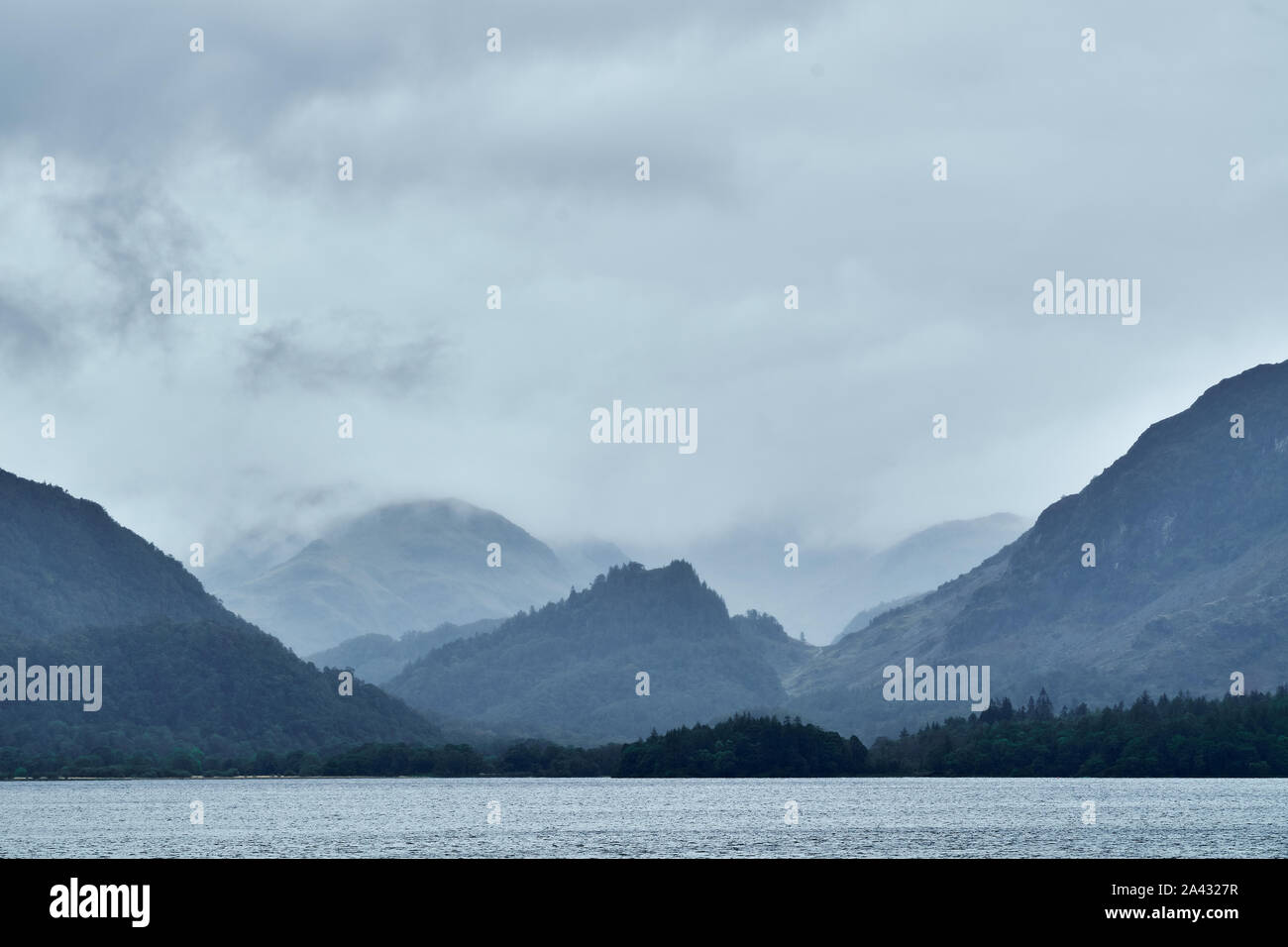Outline of mountains at the shoreline on a cloudy, rainy day at Lake ...