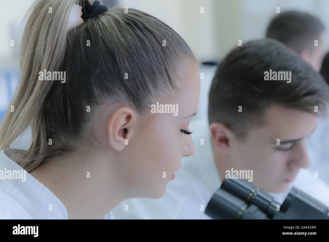 Two young male and female students scientists doing experiments in ...