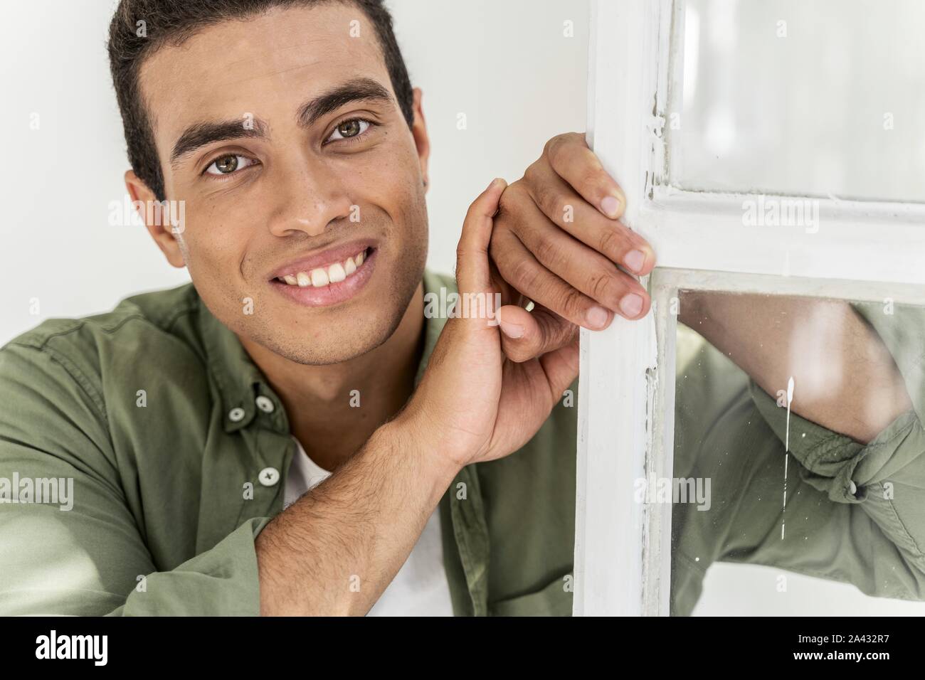 Close up picture of a cheerful young male holding the window Stock ...