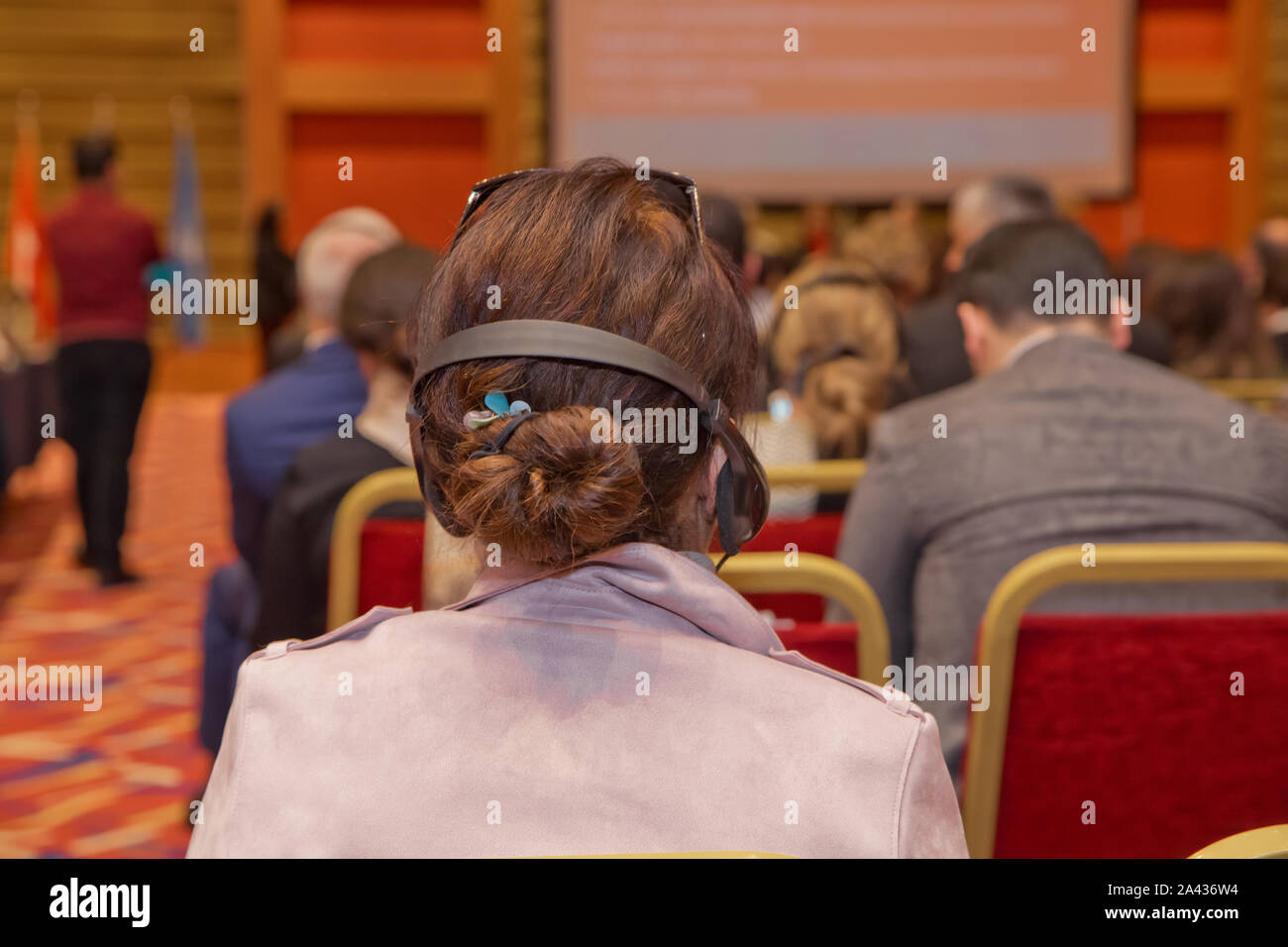 Man with headset at the conference . The audience wearing head phone ...