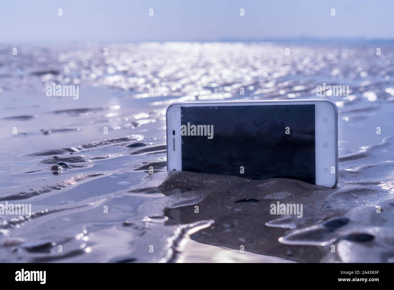 Smartphone stuck in the wet sand of the beach Stock Photo - Alamy