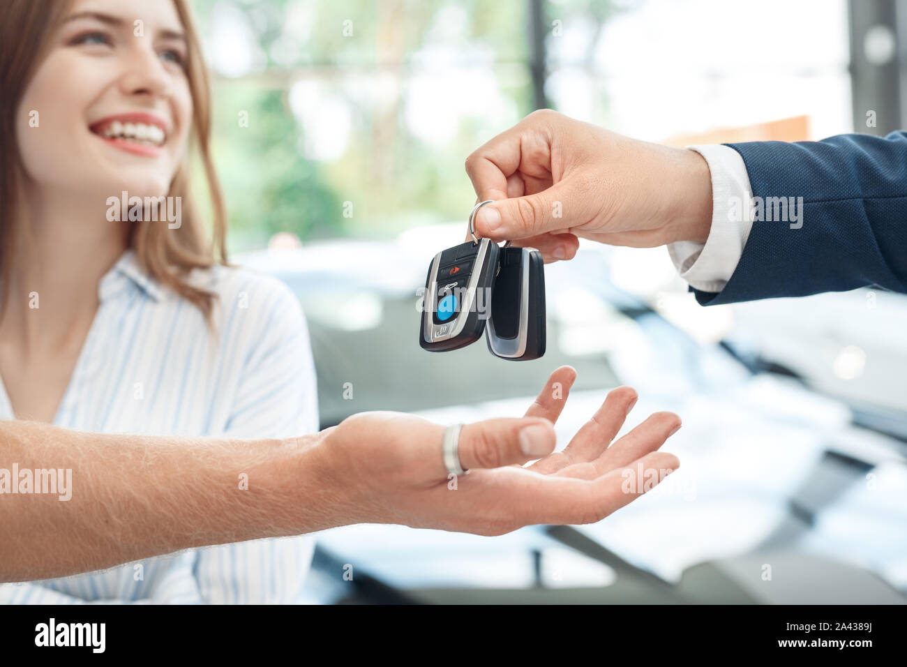 Salesman giving key from rental car to happy people Stock Photo - Alamy
