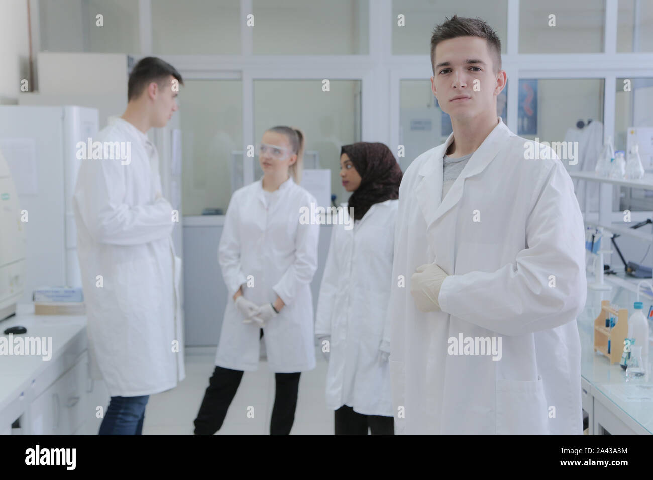 Group of young scientists doing experiments in laboratory with young ...