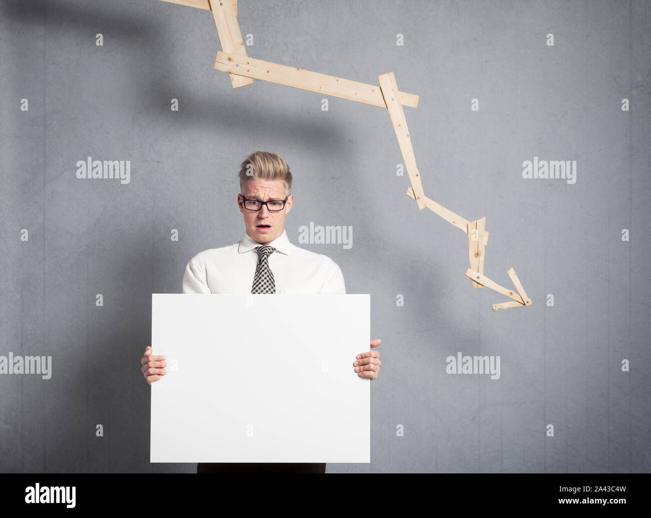 Concerned businessman presenting panel in front of descending graph ...
