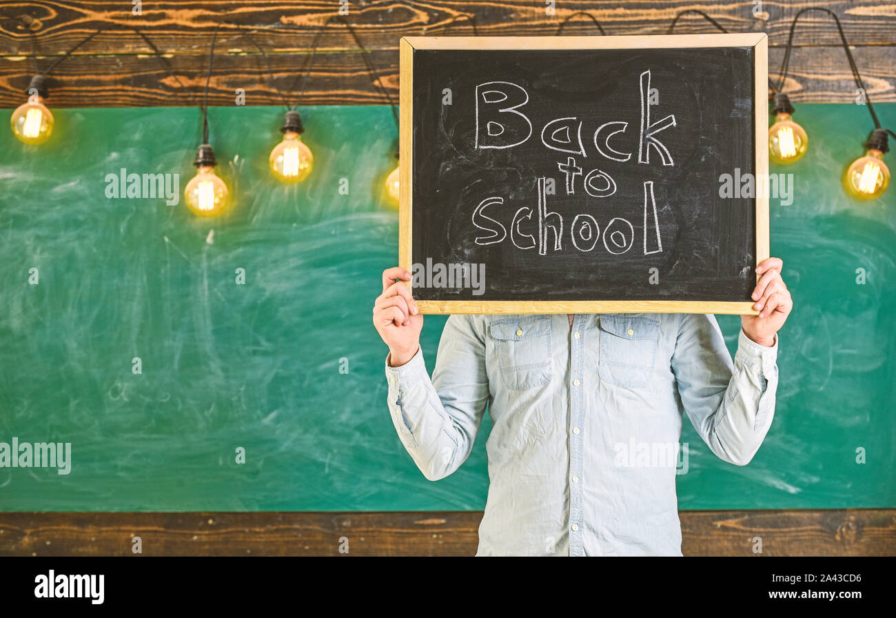 Start of school year concept. Teacher holds chalkboard in front of face ...