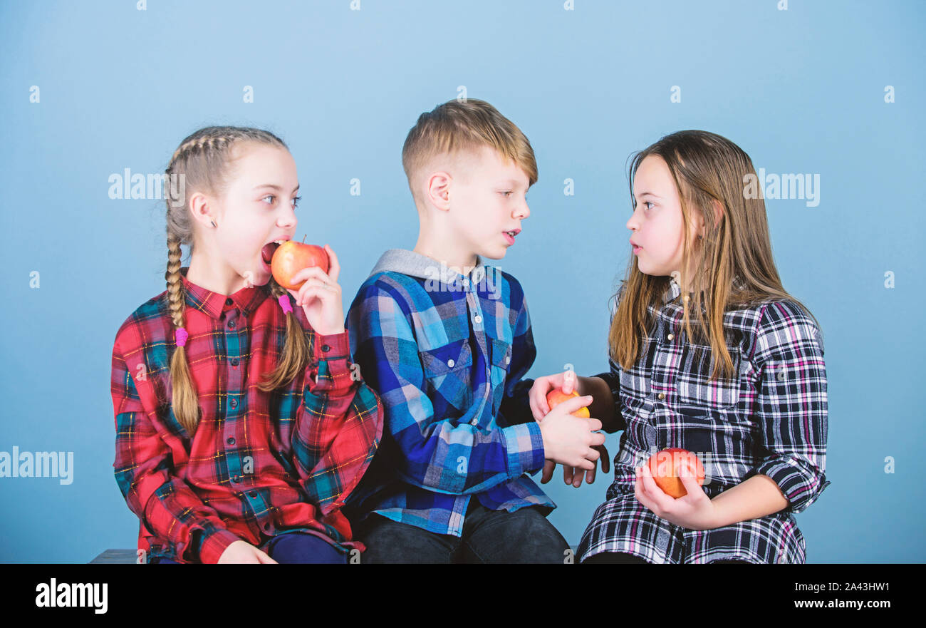 Eat fruit and be healthy. Promoting healthy nutrition. Boy and girls friends eat apple. Teens ...