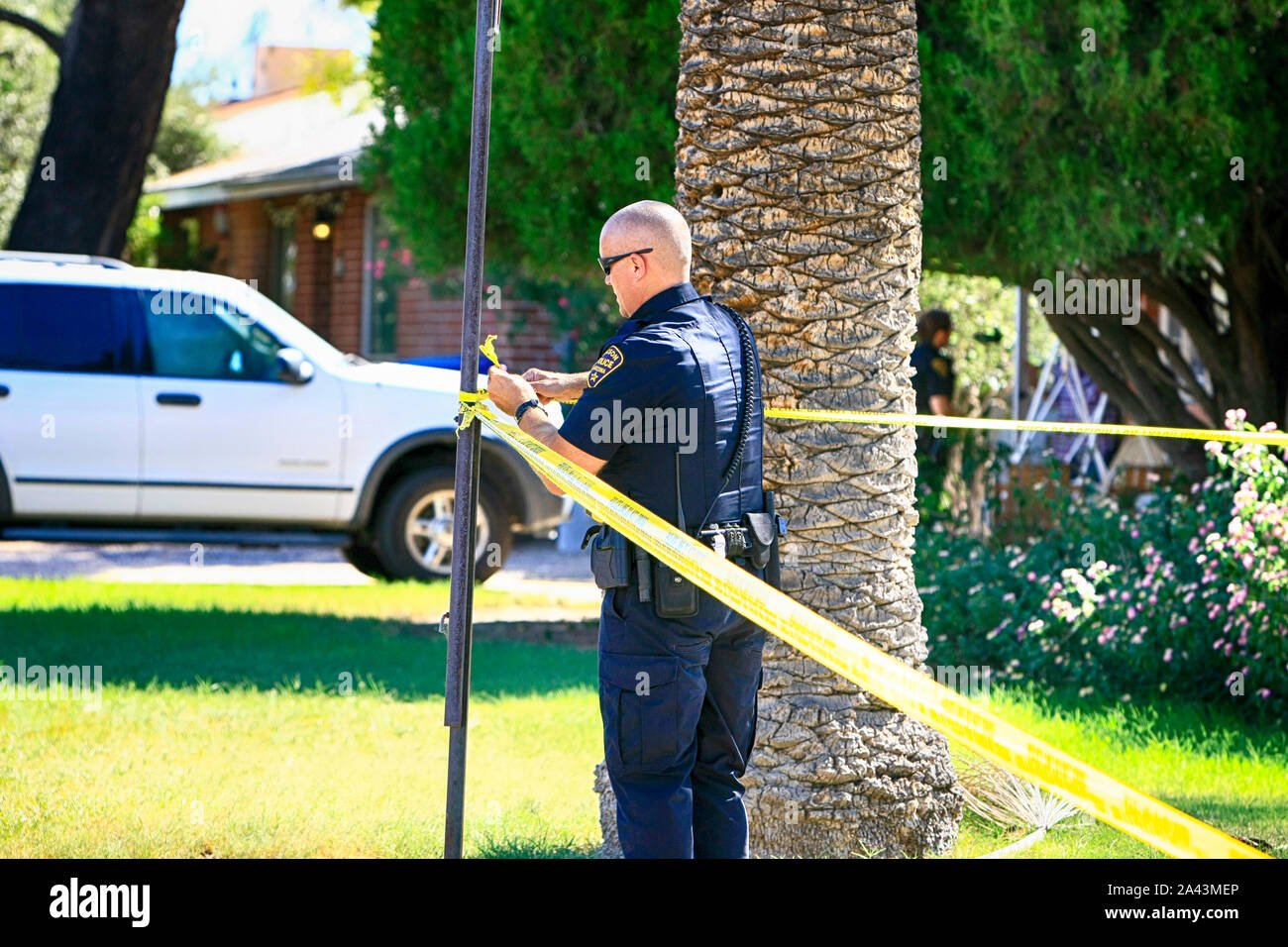 Policeman using yellow crime scene tape to seal off an area from ...