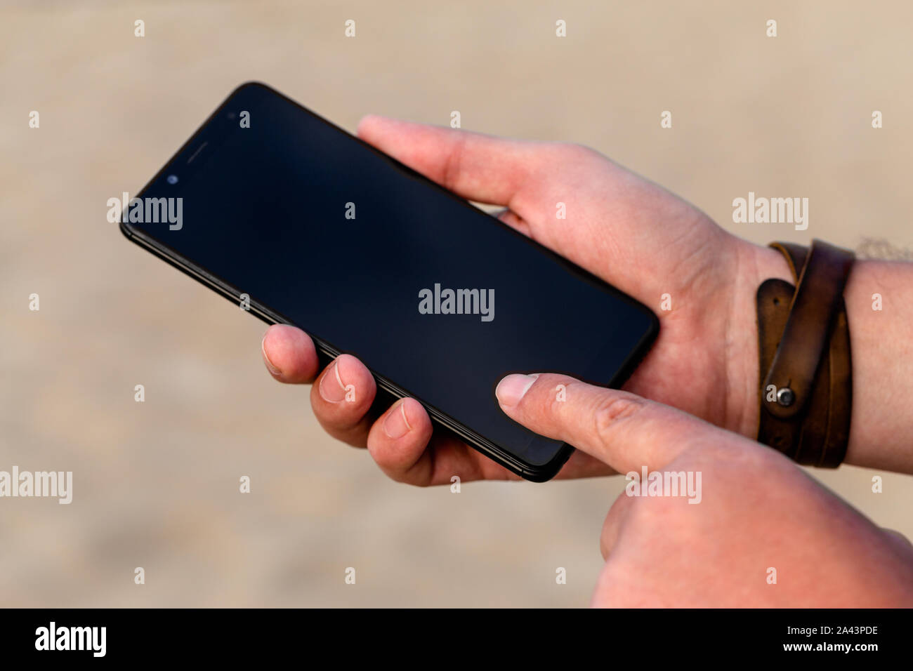 A man touching smartphone screen with his index finger on a beach sand ...