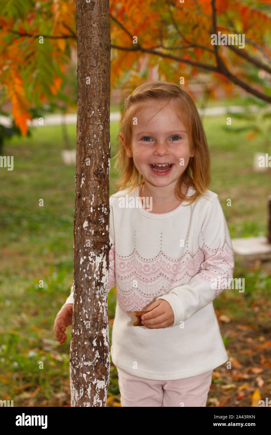 Little girl playing behind a tree hi-res stock photography and images ...