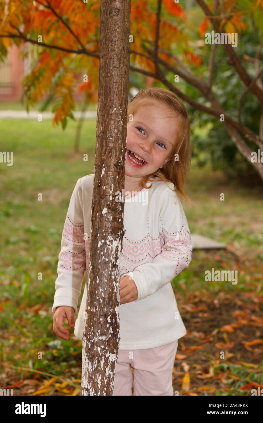 Adorable baby girl playing in a sunny park under a tree with yellow ...