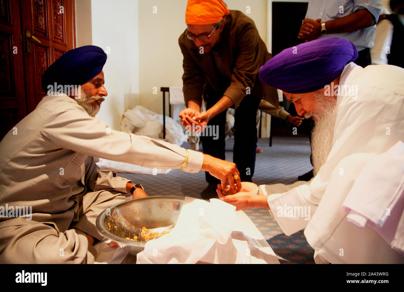 Sikh men receiving receiving karah prashad following the end of worship ...