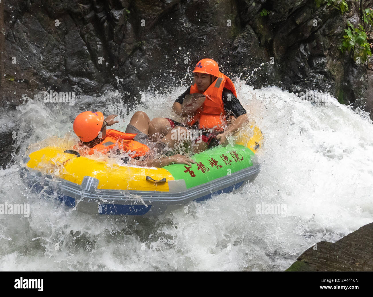 A crowd of tourists sitting on inflatable rafts jam a stream and catch ...